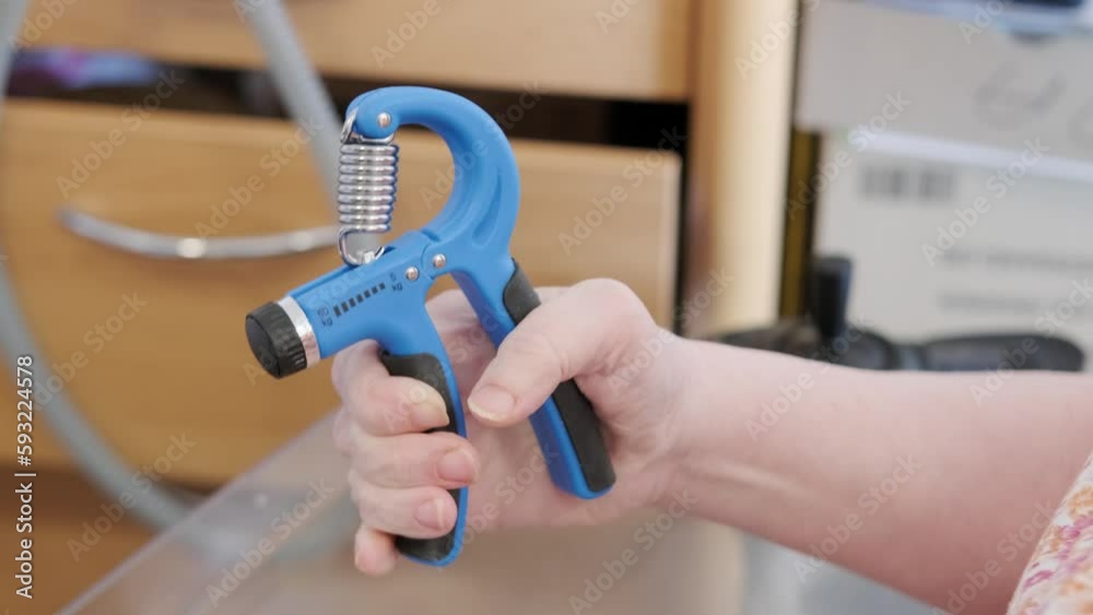 close-up female hand compresses spring expander, disabled elderly woman ...