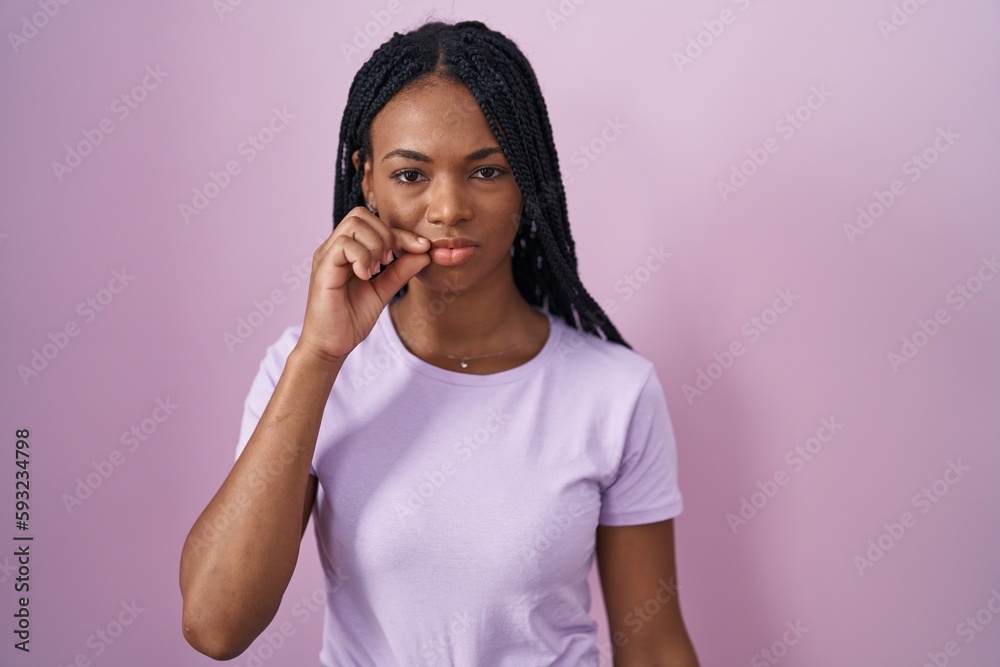 African american woman with braids standing over pink background mouth ...