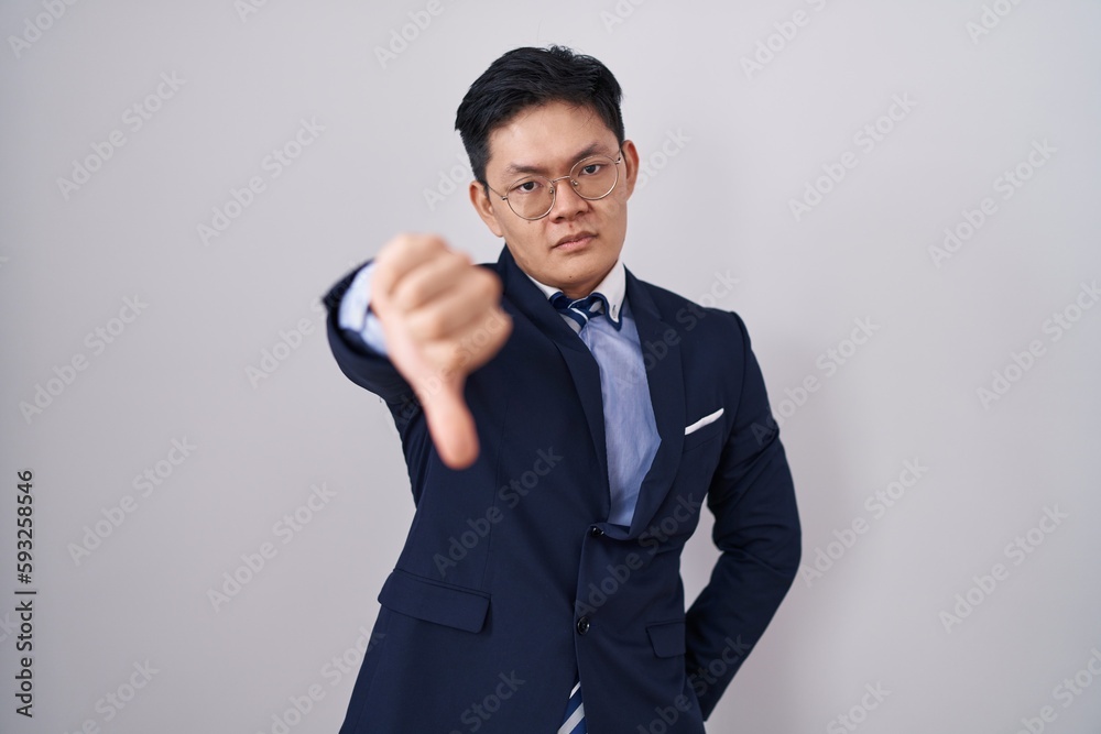 Young asian man wearing business suit and tie looking unhappy and angry ...