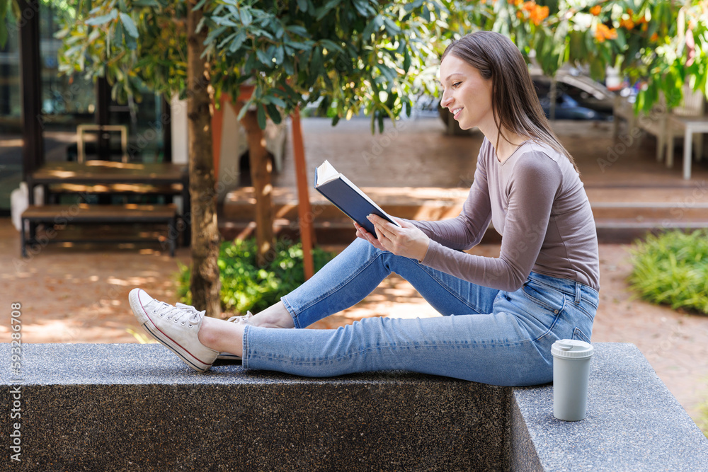 Student Woman sit and read book on the benches along the corridor in ...