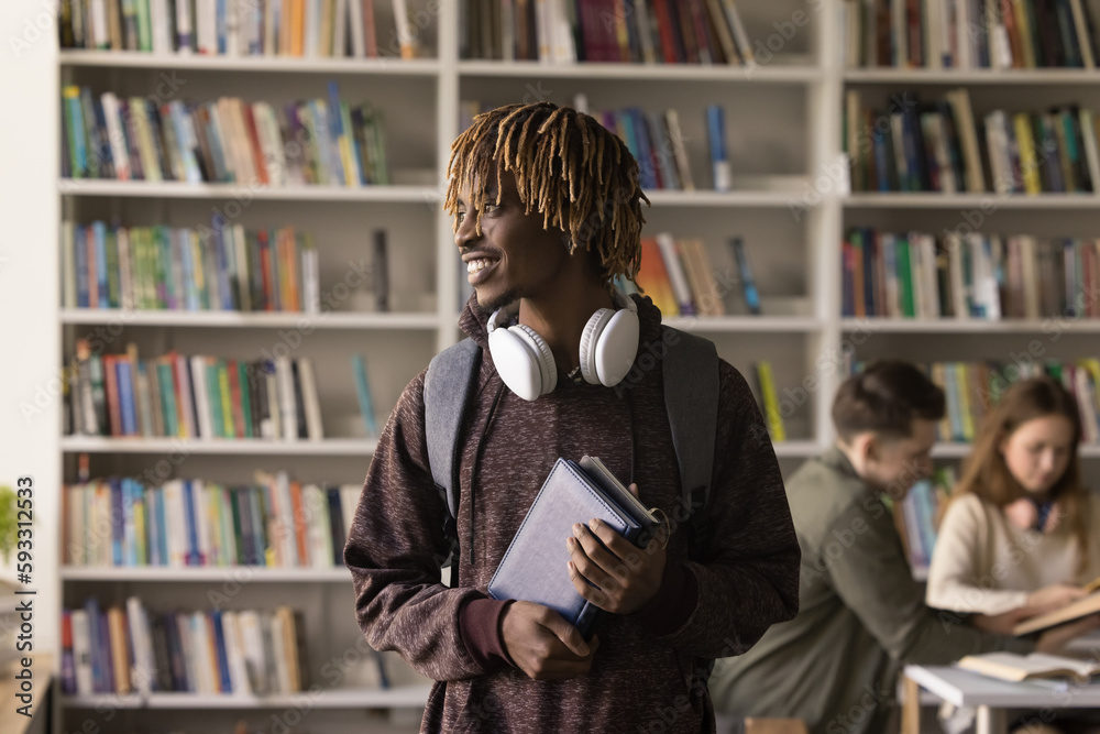Young African student guy pose in library with schoolmates on ...