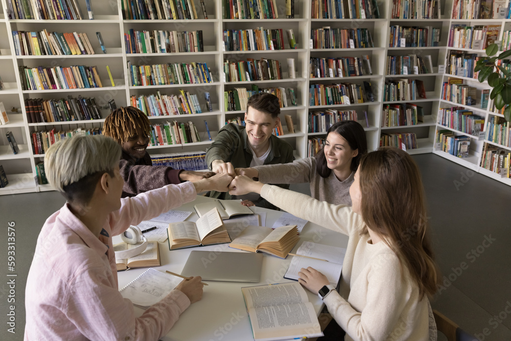 Happy multi ethnic group of university students sit at desk with books ...