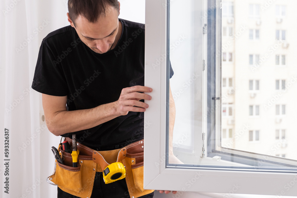 Handsome young man installing bay window in a new house construction ...