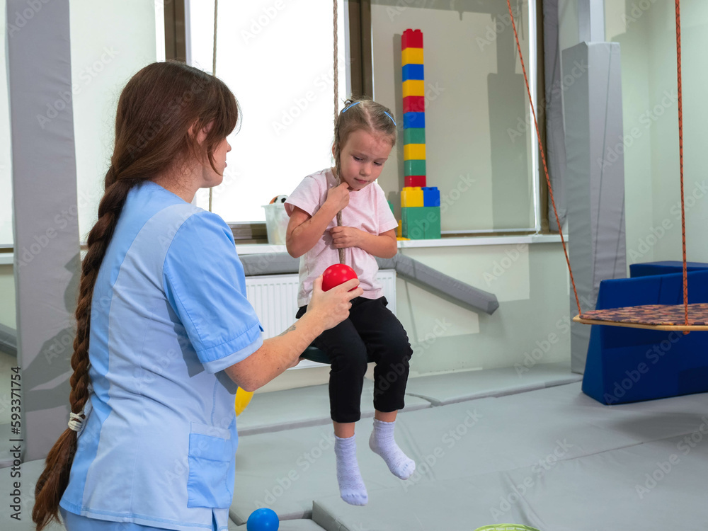 Child with physiotherapist on swing during sensory integration session ...