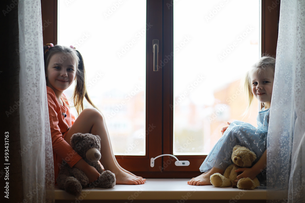 Beautiful little girl smiling and watching out the window. A child ...