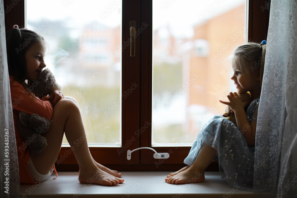 Beautiful little girl smiling and watching out the window. A child ...
