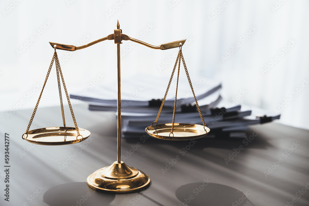 Shiny golden balanced scale and pile of legal paper on desk in lawyer ...