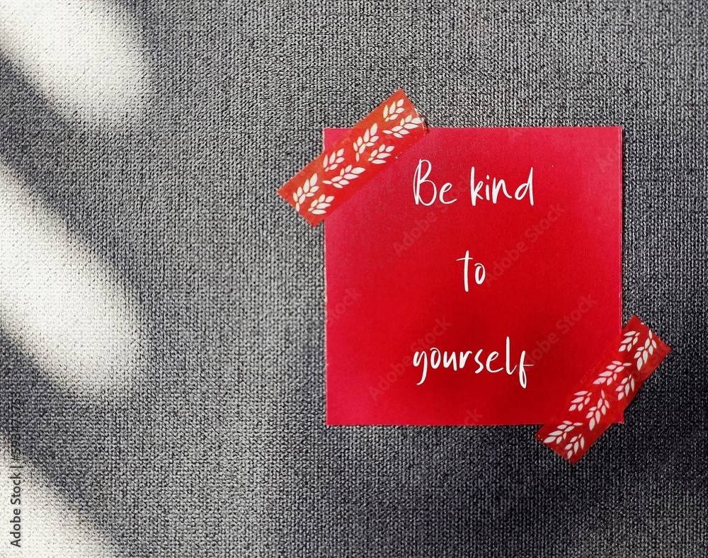 Red note stick on wallpaper background with handwritten text BE KIND TO ...
