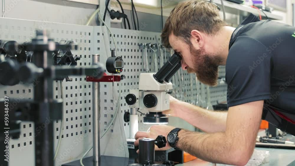 Diagnostics of diesel injectors under a microscope. The master examines ...