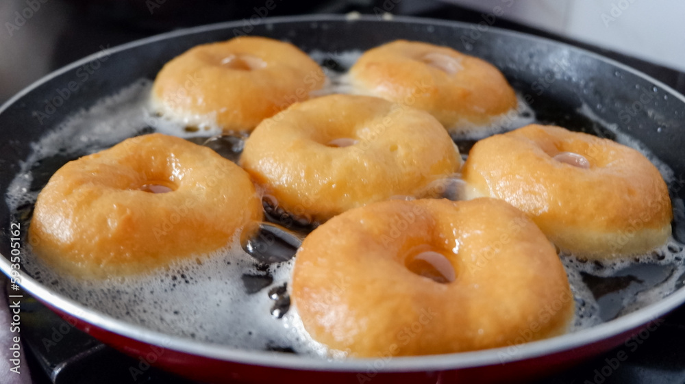 Donuts frying in deep fat. Preparation of traditional donuts, six round ...