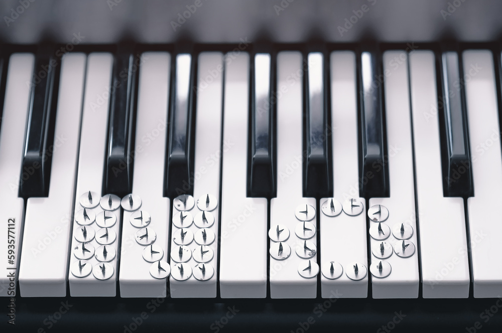 Piano keyboard. Thumbtacks are laid out on the keys of a musical ...