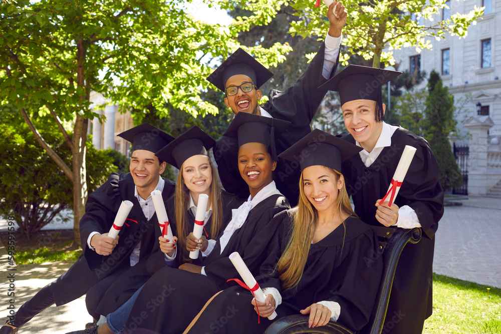 Laughing excited group of multicultural people in graduation gowns and ...