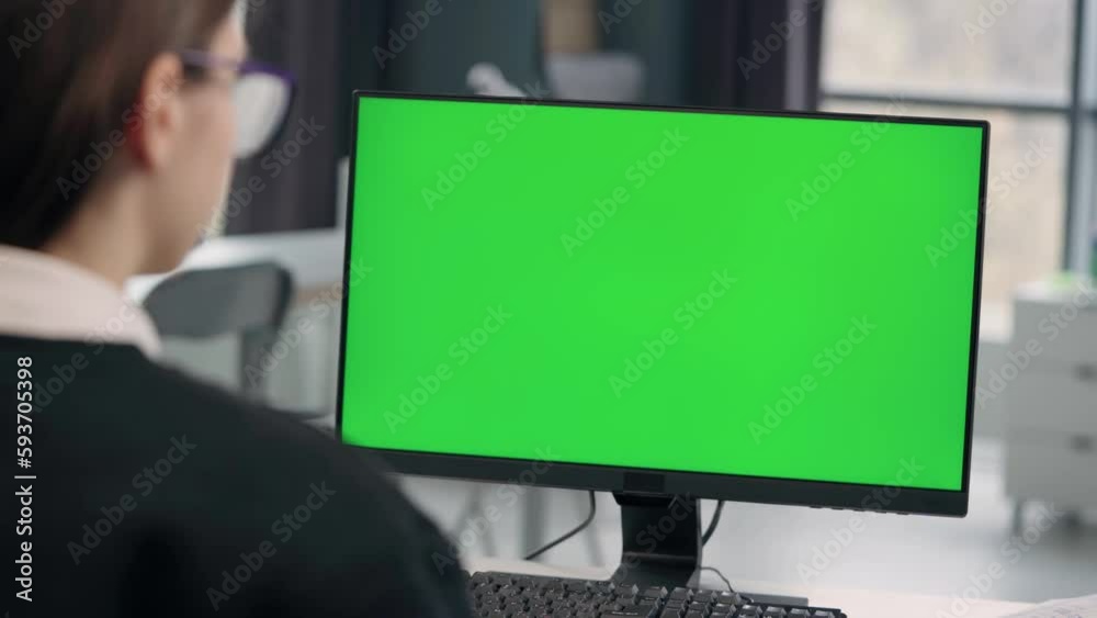 Young Girl Working At Computer With Green Mock Up Screen in Office ...