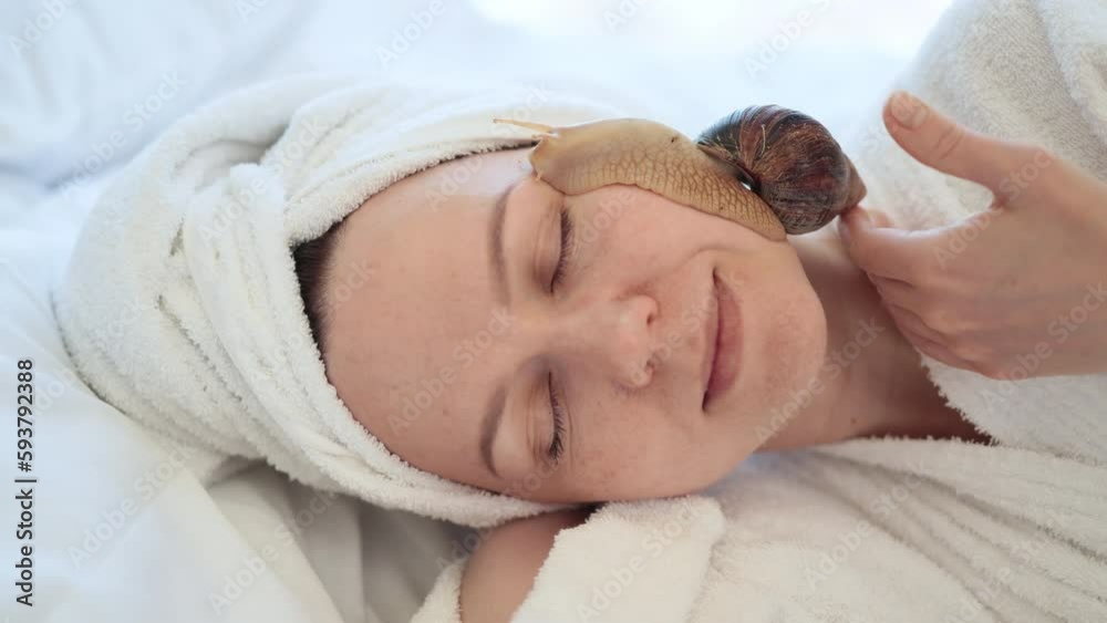 Carefree young lady in after-bath wear lying on white soft bed with ...