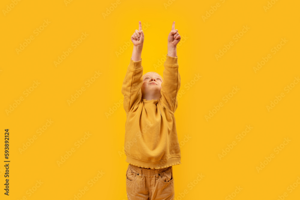 Little girl raised hands up and points index fingers up. Copy space ...