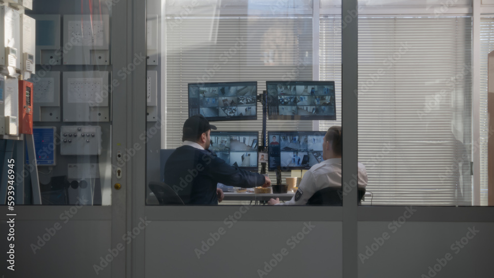 Two security officers control CCTV cameras on computers during lunch ...