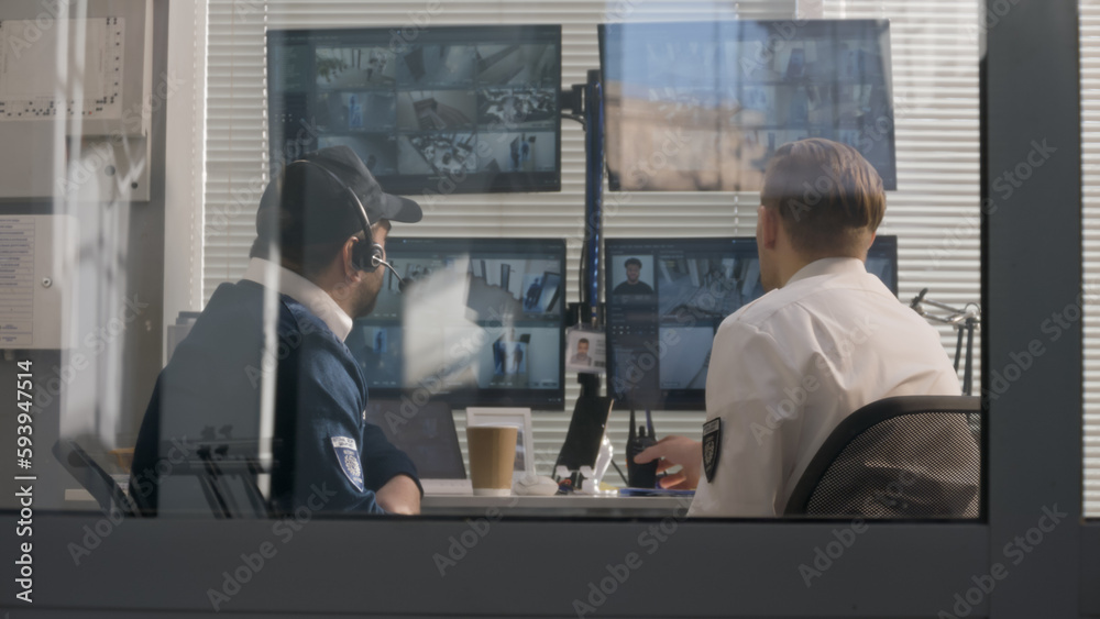 Foto de Security officers sit in surveillance room and monitor CCTV ...