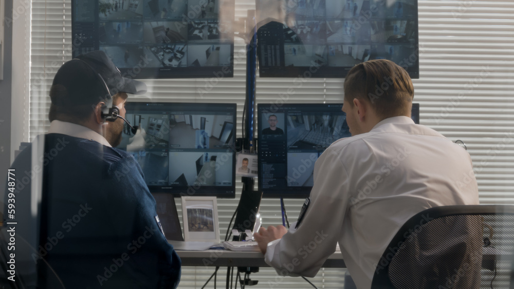 Foto de Security officers sit in surveillance room and monitor CCTV ...