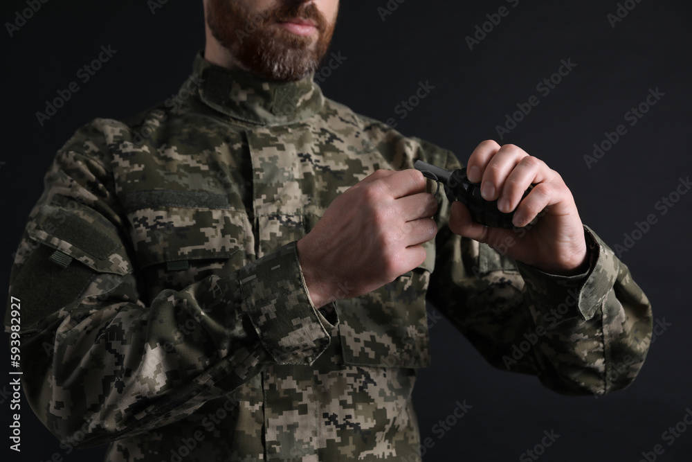Soldier pulling safety pin out of hand grenade on black background ...