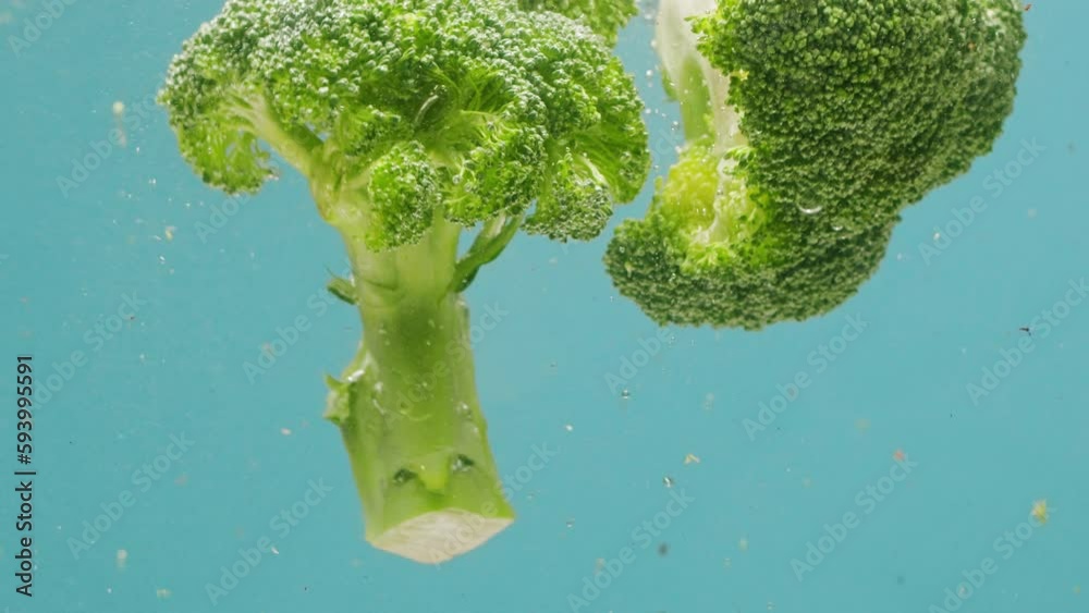Green broccoli falling in boiling water, fresh fruits and vegetables ...