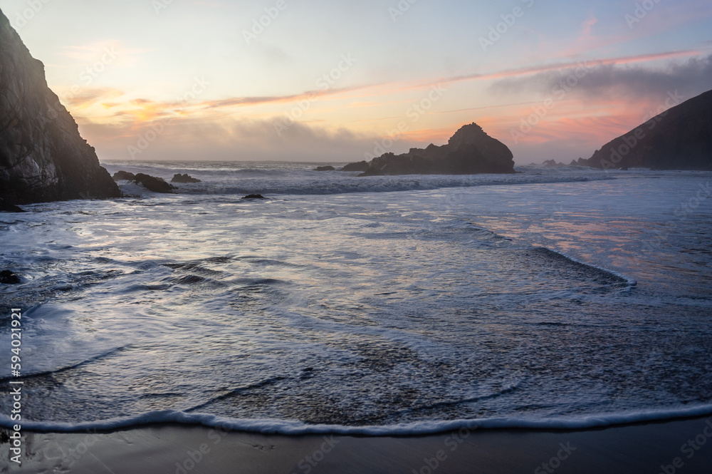 Tidal waves flowing out at Pfeiffer beach, while it is enshrouded by a ...