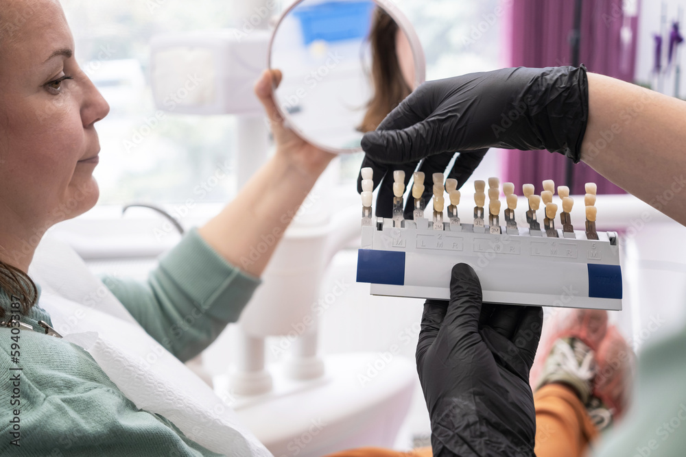 Dentist hand holding teeth color samples helping patient to choose ...