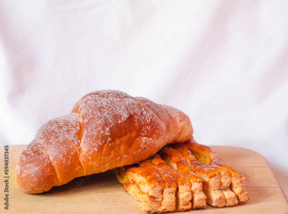 Dos panes dulces, uno sobre otro en fondo blanco sobre una tabla de ...