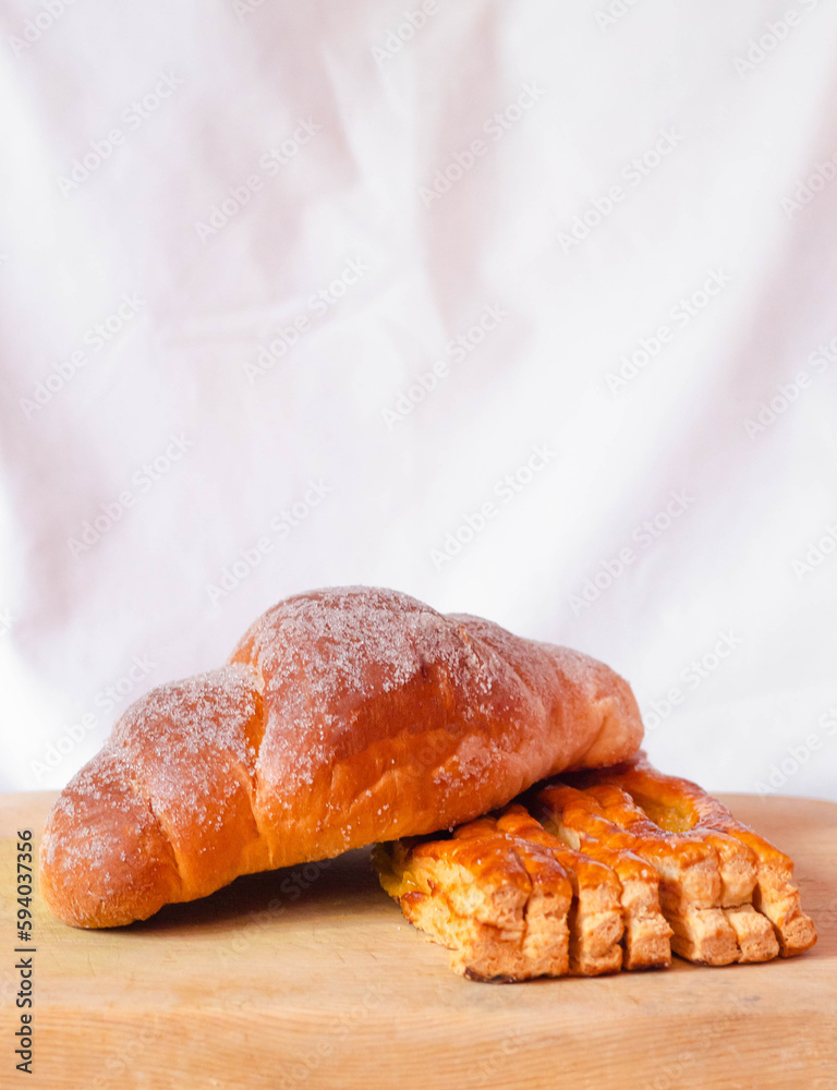 Dos panes dulces, uno sobre otro en fondo blanco sobre una tabla de ...