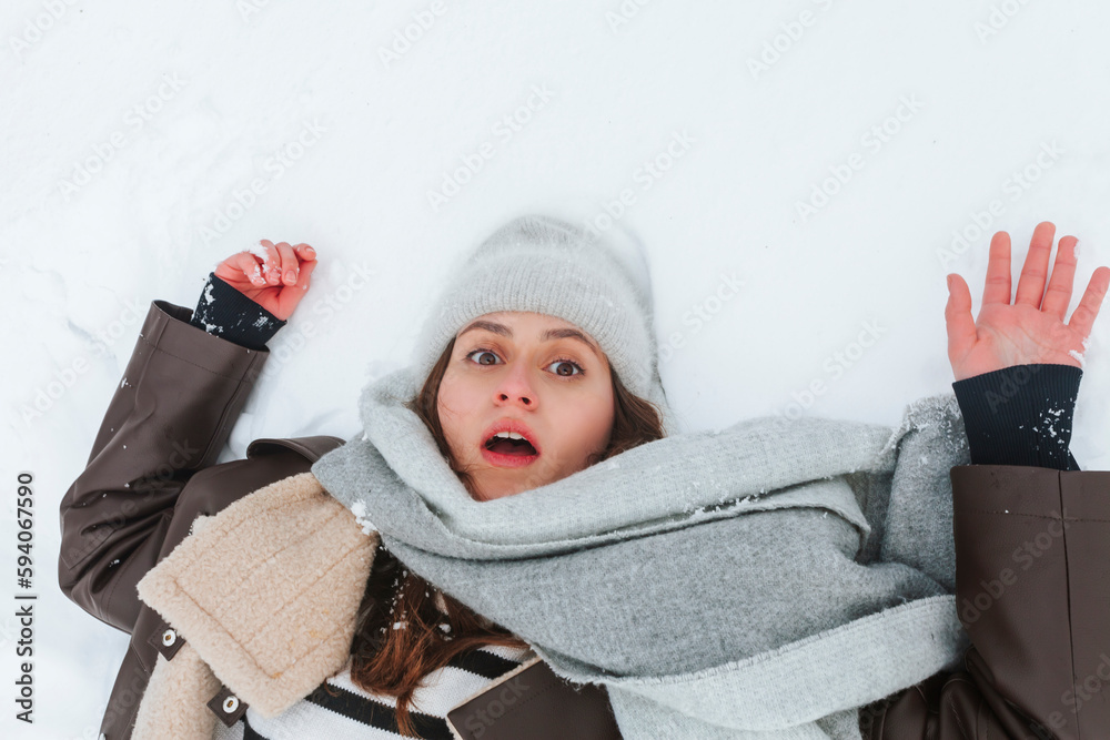 Surprised and shocked brunette girl lying on the snow. Woman slipped ...