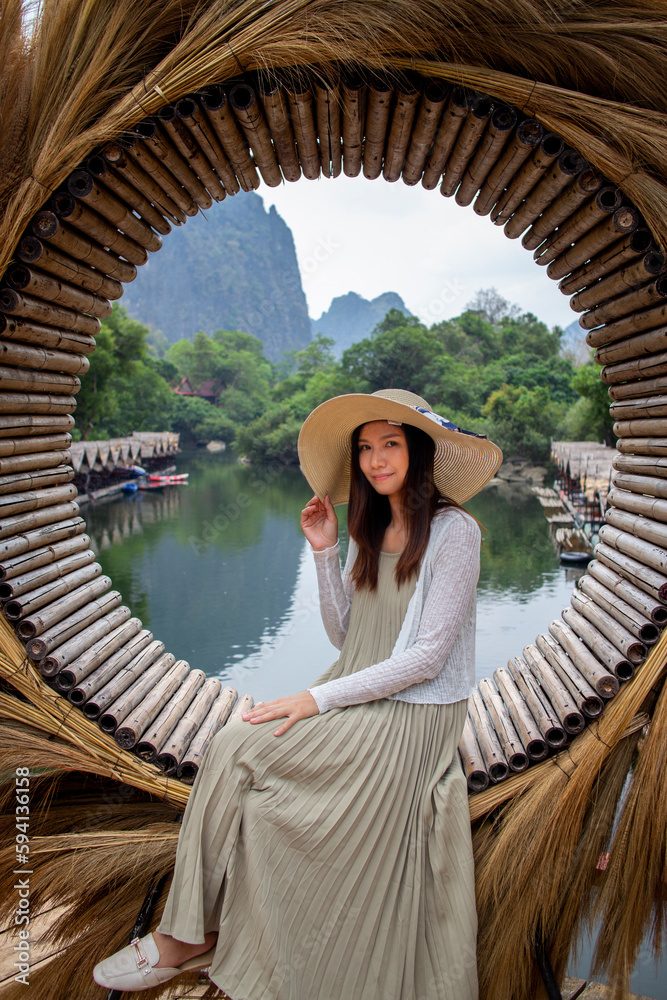 Asian women wearing fashionable wicker hats sit on circular bamboo ...