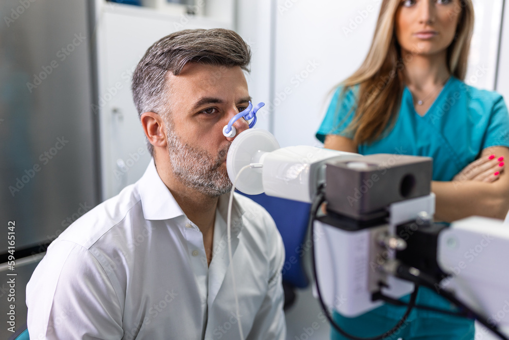 Man Performing Pulmonary Function Test And Spirometry Using Spirometer