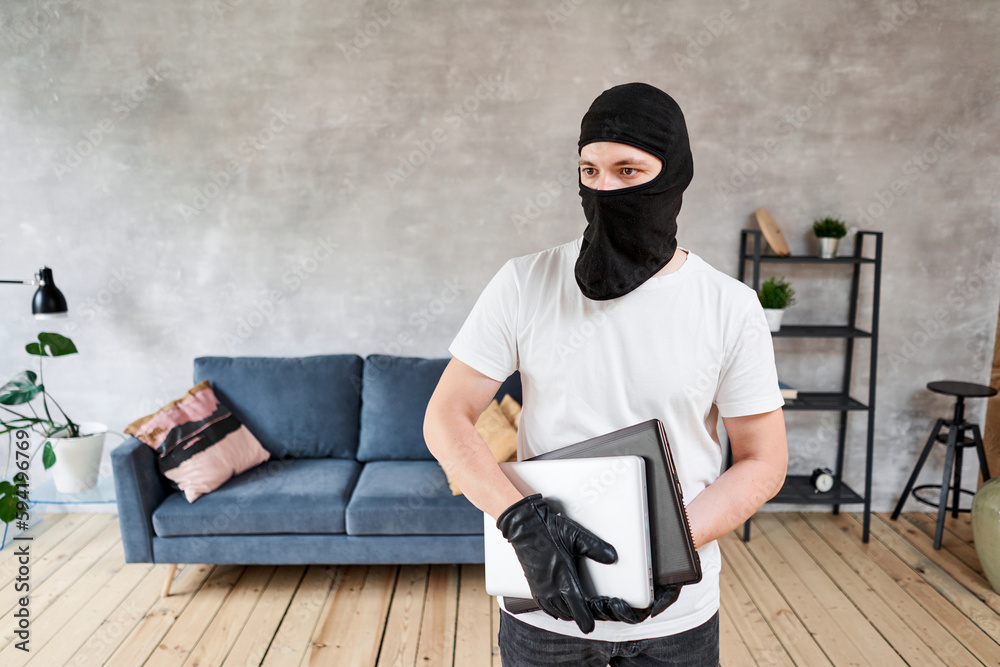 Masked face. Man burglar stealing tv set from house. Thief with black ...