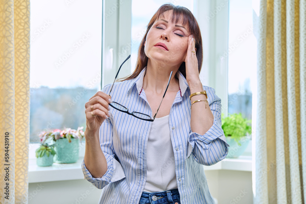 Sad mature woman experiencing health problems near window at home Stock ...