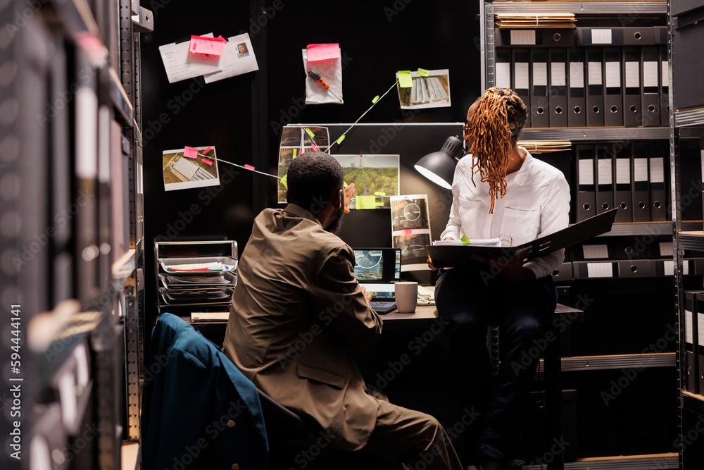 Detective partners analyzing surveillance photos hanging on evidence ...
