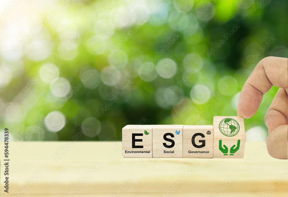 Hand flip wooden cubes with green globe icon with ESG text on bokeh ...