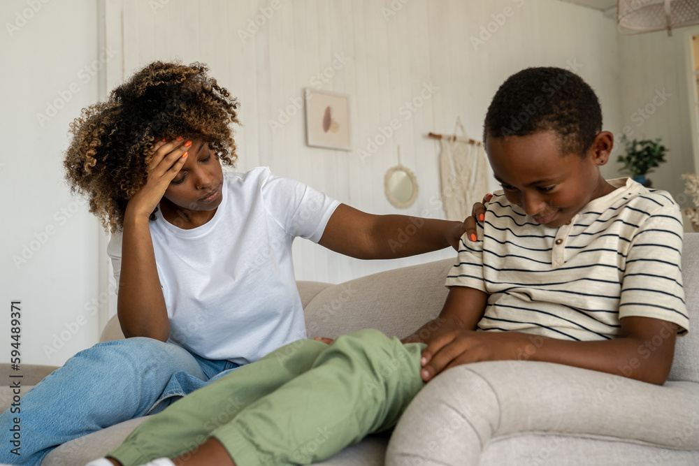 Foto de Exhausted African American mother grabs head from antics of kid ...