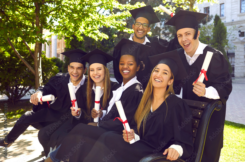 Group of laughing multicultural people in graduation gowns and caps ...