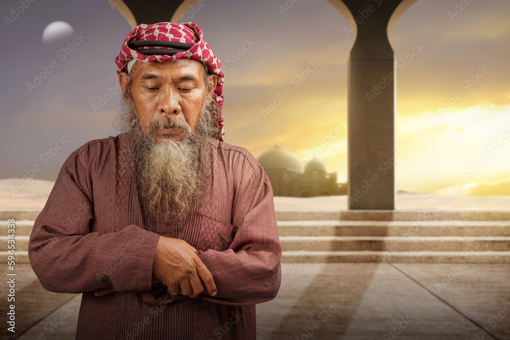 Muslim man with a beard wearing keffiyeh with agal in praying position ...