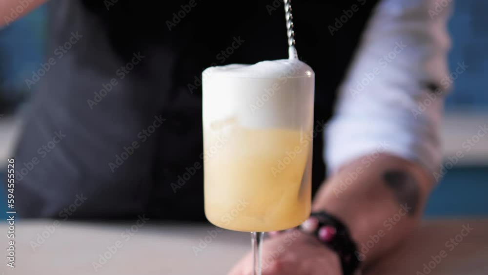Close-up shot of alcoholic cocktail. Bartender mixes all drink's ...