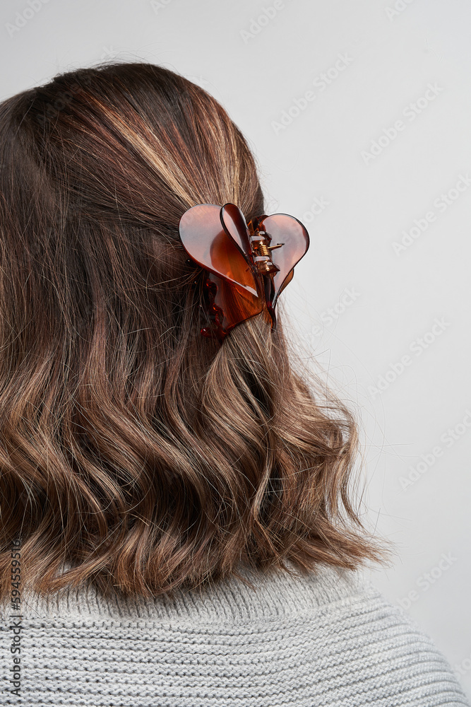 Cropped back shot of a brown-haired girl in a knitted sweater. The lady ...