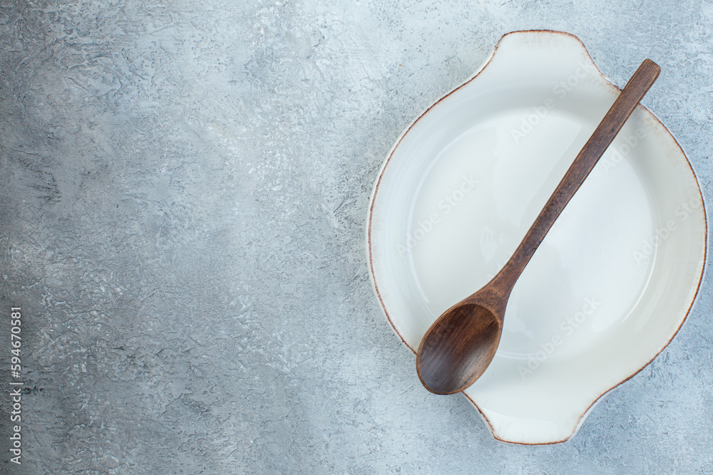 Wooden spoon in empty white soup plate on the left side on half dark ...