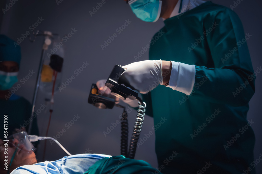 Doctors and team performing using defibrillator to give electrical ...