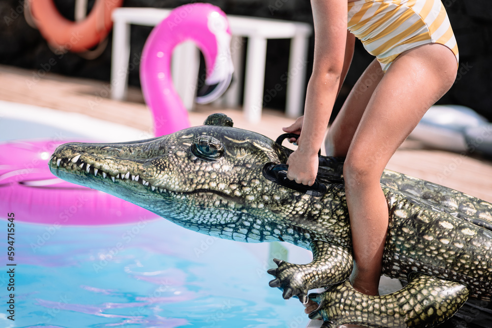 Crop kid on inflatable crocodile in pool Stock Photo | Adobe Stock
