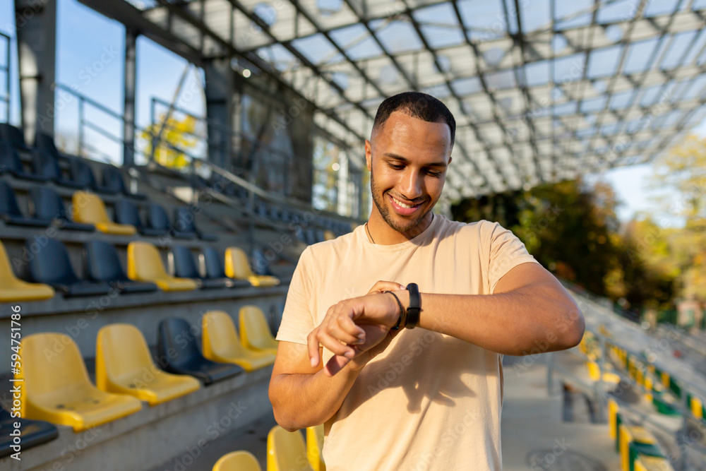 Young Latin American male sportsman stands at the stadium and looks at ...