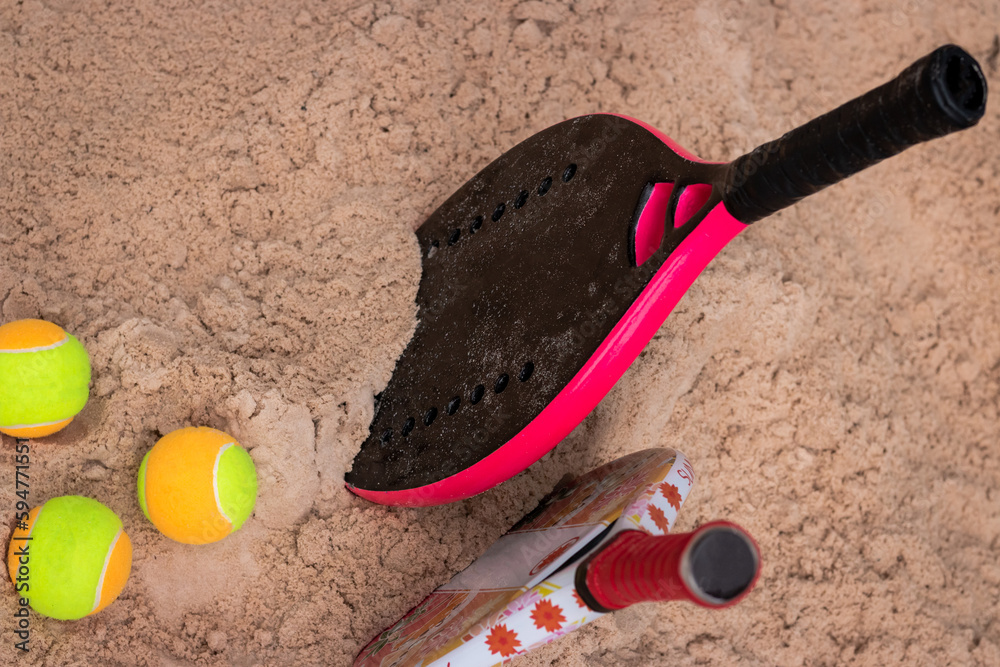 Women's and children's beach tennis rackets buried in the sand. Beach ...
