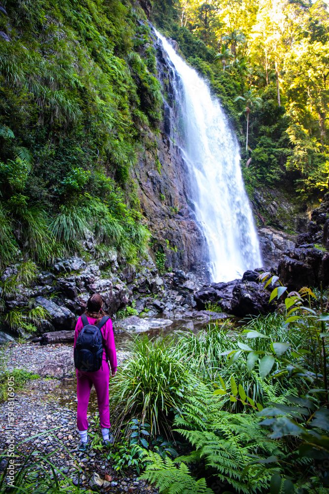 hiker girl standing in front of large tropical waterfall in australian ...