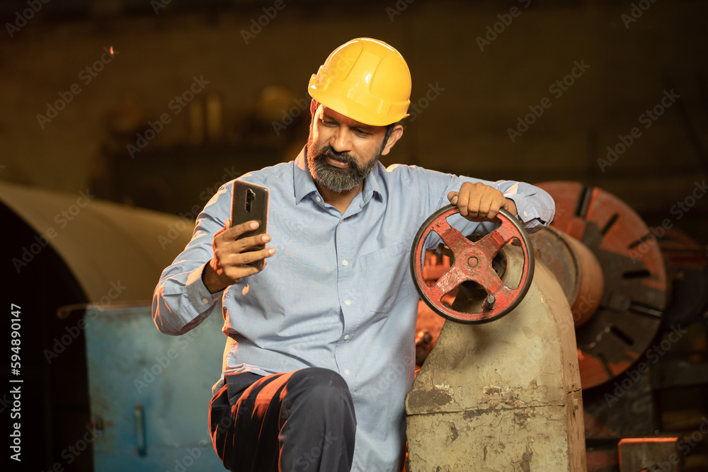 Portrait of happy Indian male Mechanical Engineer wearing yellow helmet ...