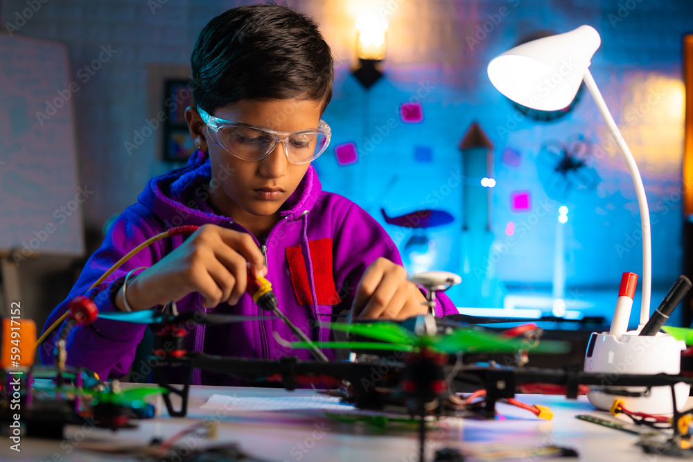 Intelligent serious indian kid busy making drone connections by ...