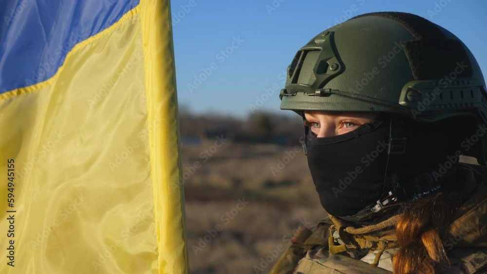 Dolly shot of girl in military helmet and balaclava holds a waving ...