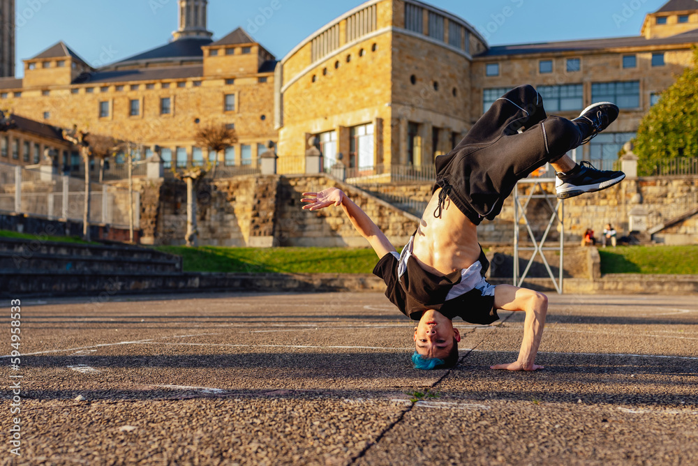 horizontal photograph of street dancer performing an acrobatic stunt ...